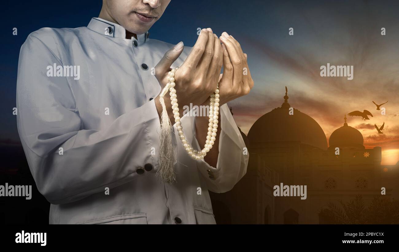 Muslim man standing while raised hands holding prayer beads and praying ...