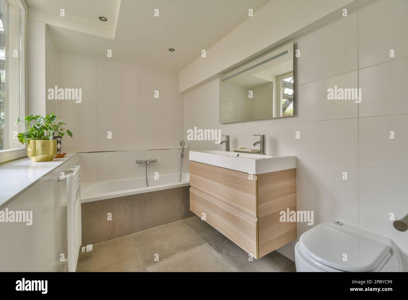 Modern bathroom with bathtub and sinks placed under mirror near toilet ...