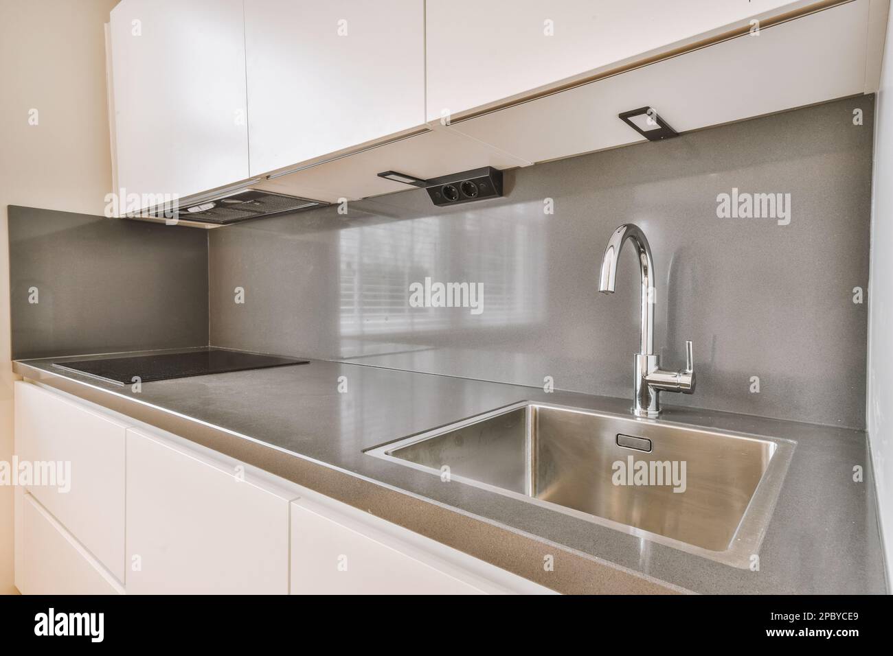 Gray kitchen counter with chrome faucet and sink installed near stove ...