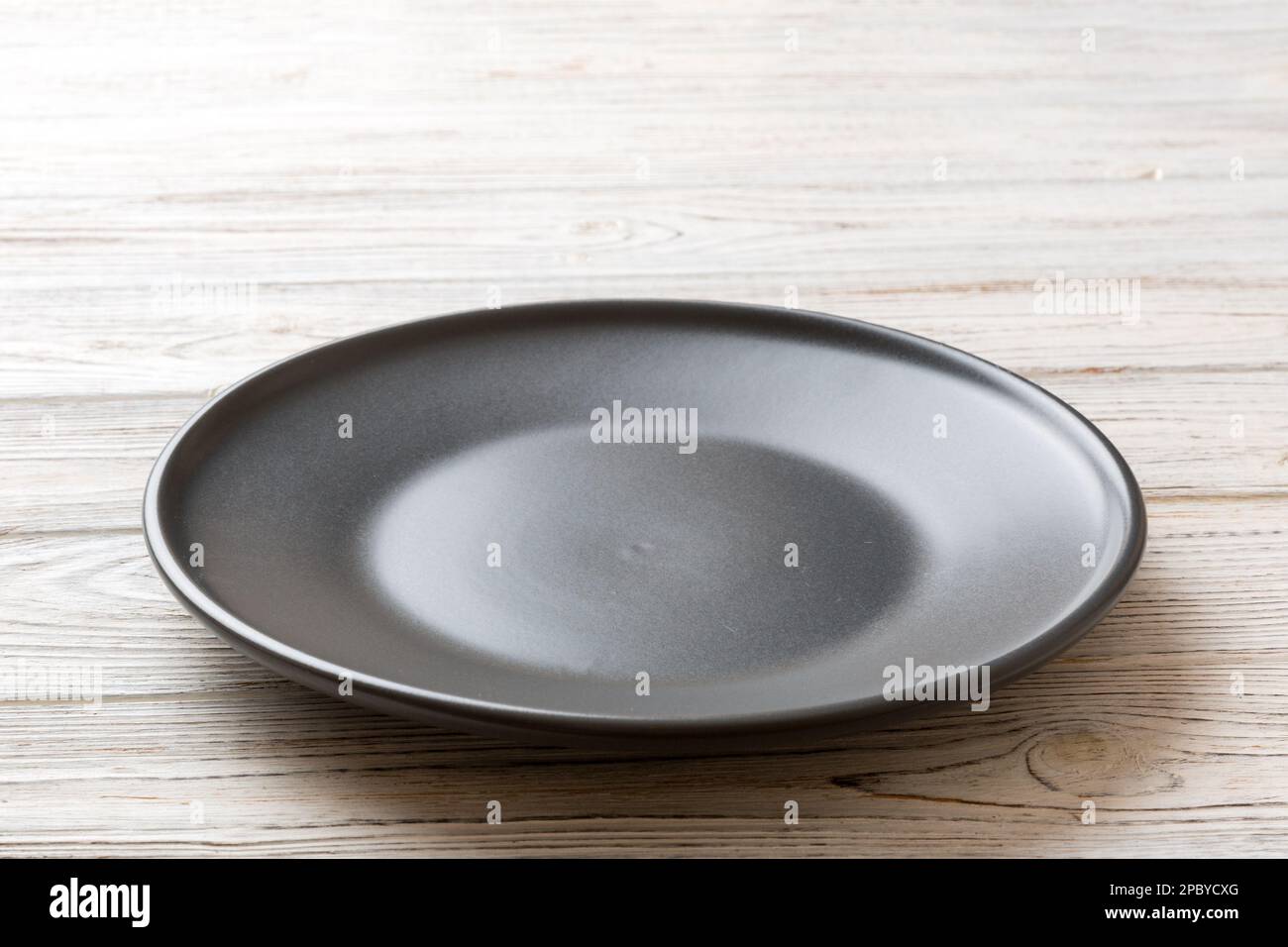 Perspective view of empty black plate on wooden background. Empty space ...