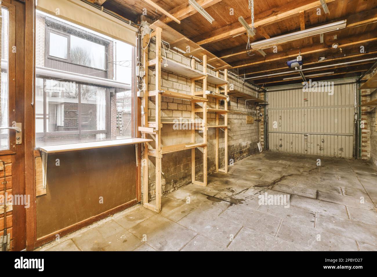 Interior of old shabby garage with brick walls and shelves near ...