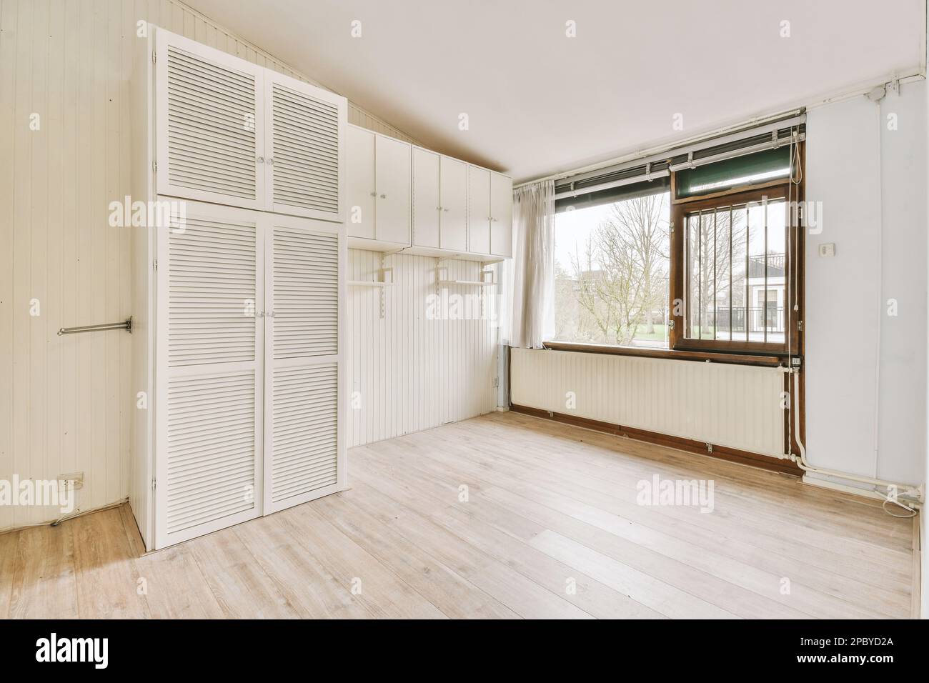 Interior of light room with white wardrobe and shelves placed under ...