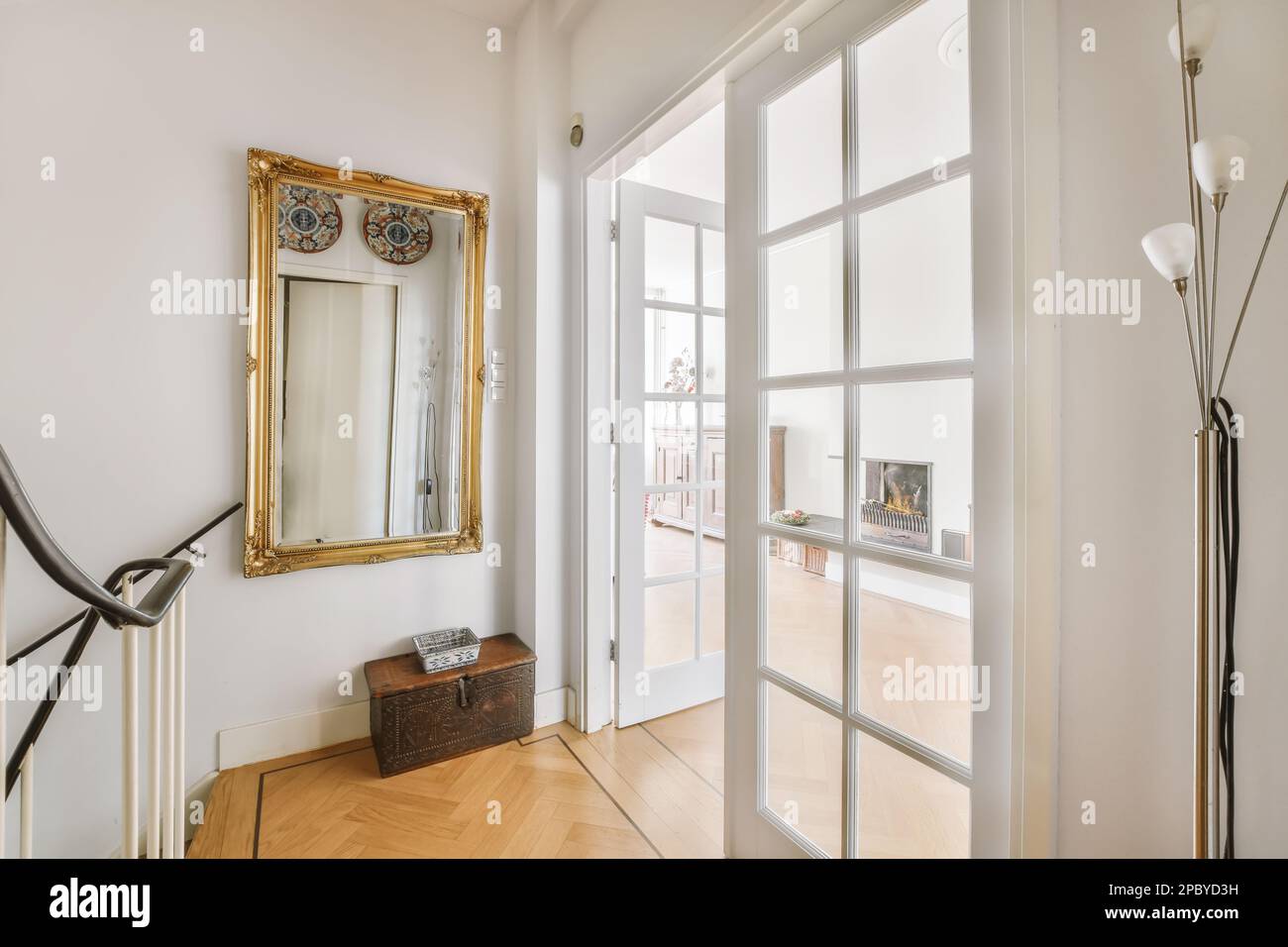 Interior of hall with staircase and mirror near white French doors in ...