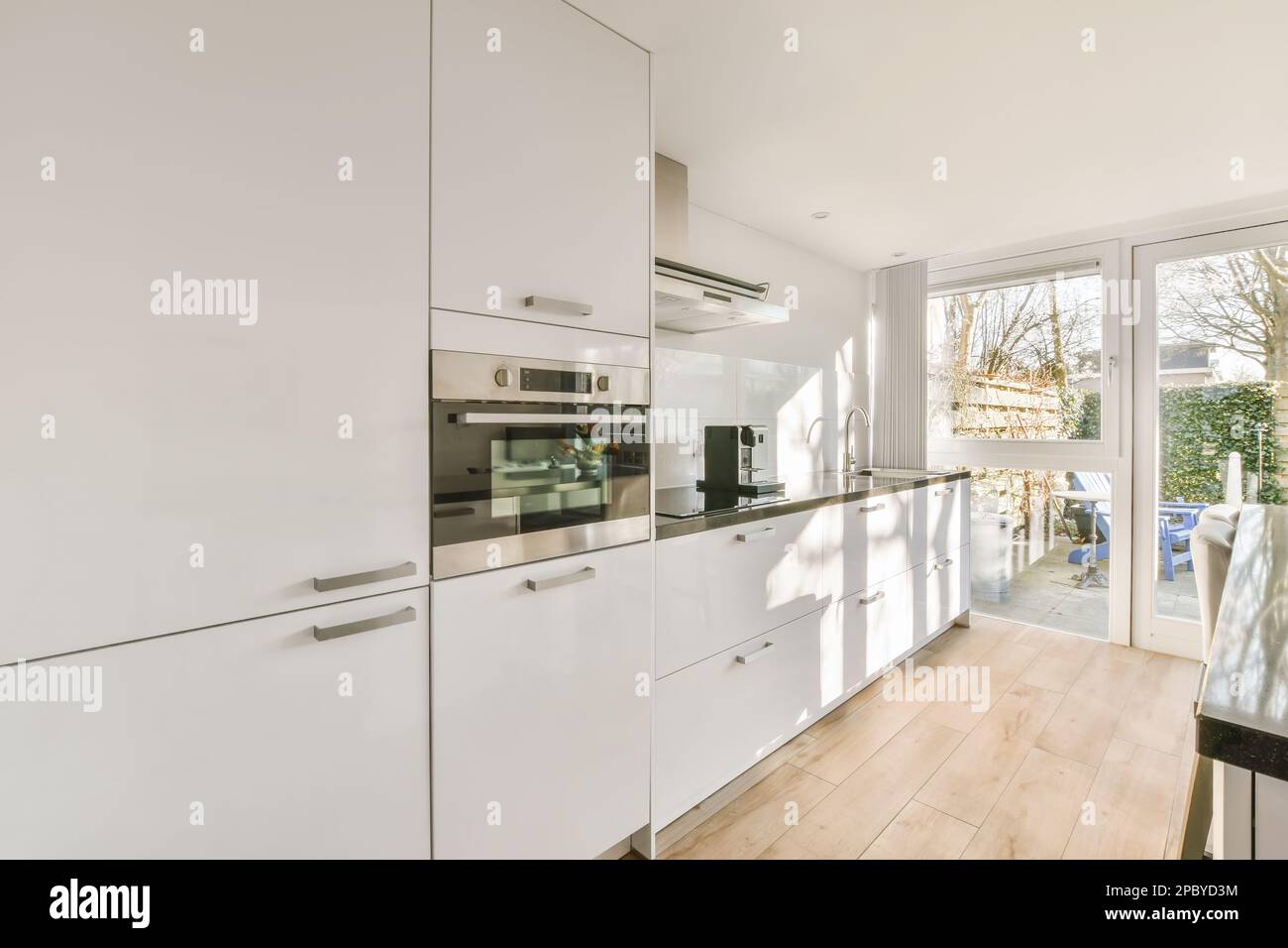 Interior of stylish open plan kitchen with white cabinets and built in ...