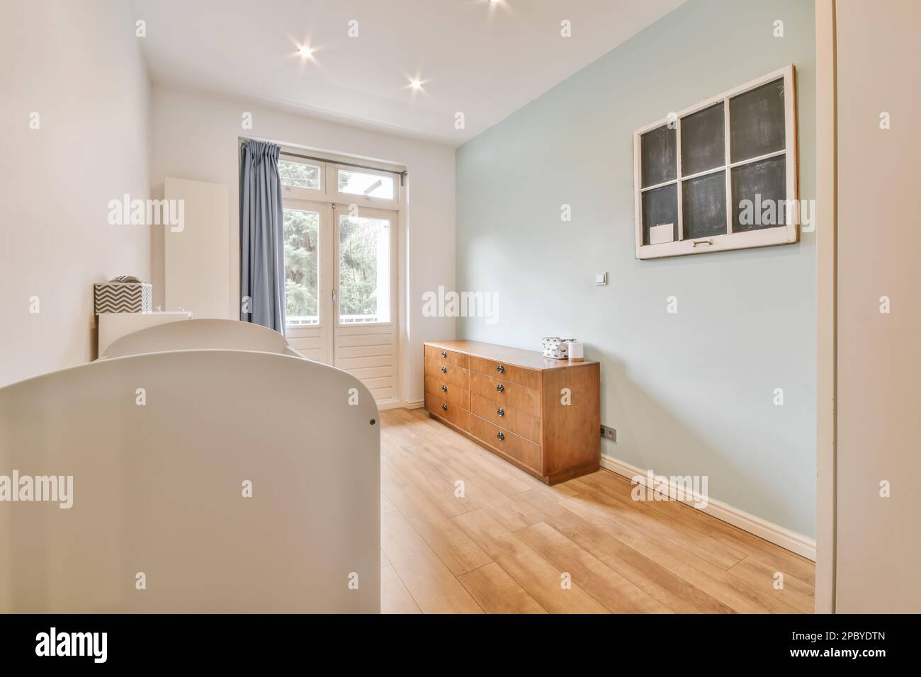 Interior design of light bedroom with white crib placed against wooden ...