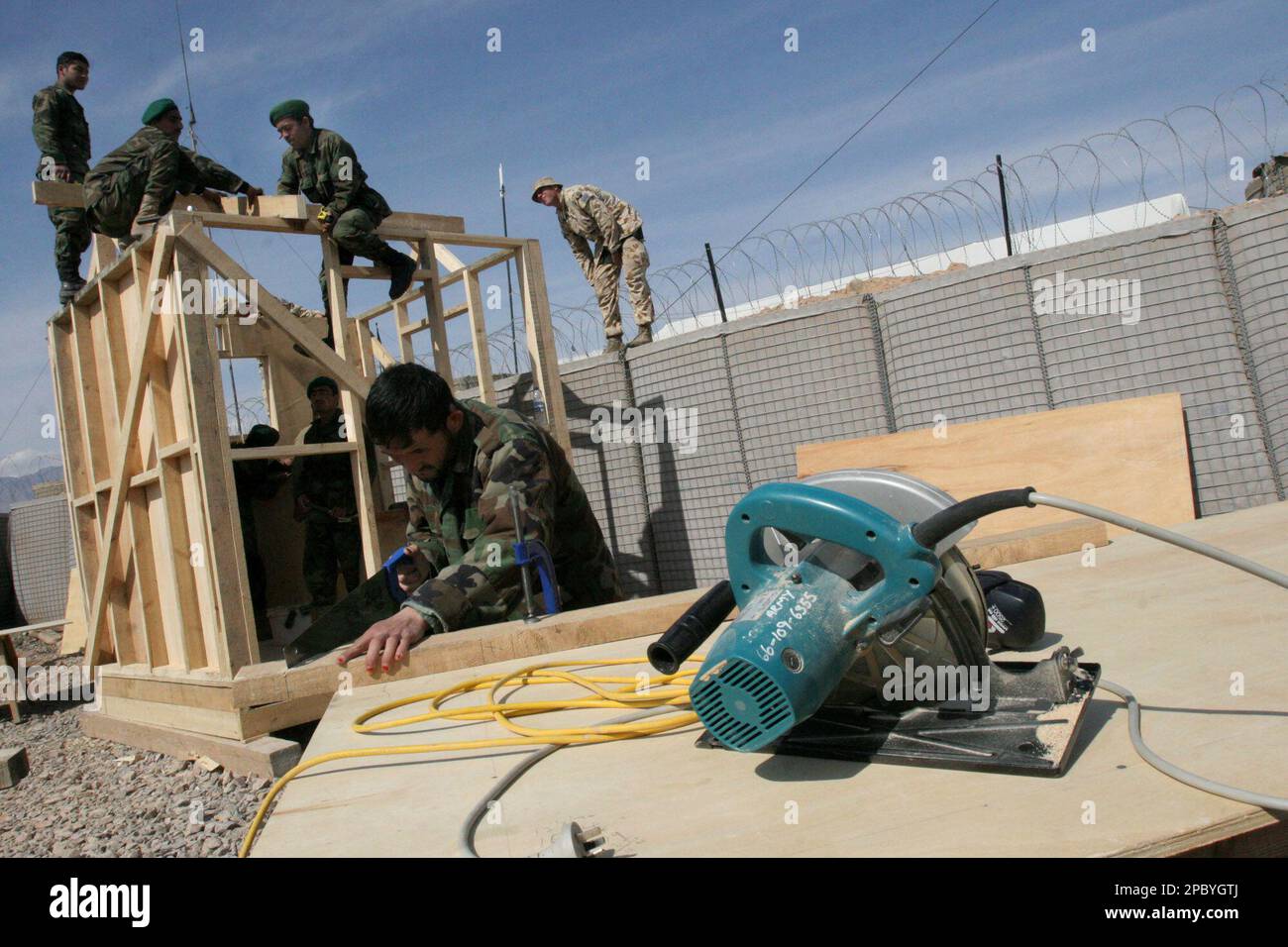 A soldier of Afghan National Army saws a stick as he helps his ...