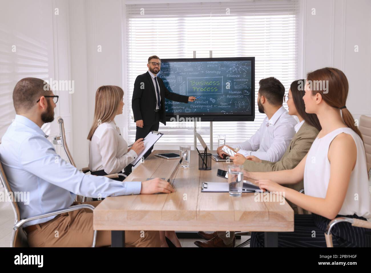 Business trainer using interactive board in meeting room during ...