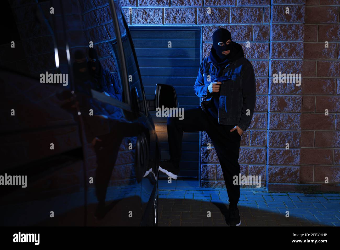 Man in balaclava with gun near van outdoors Stock Photo - Alamy
