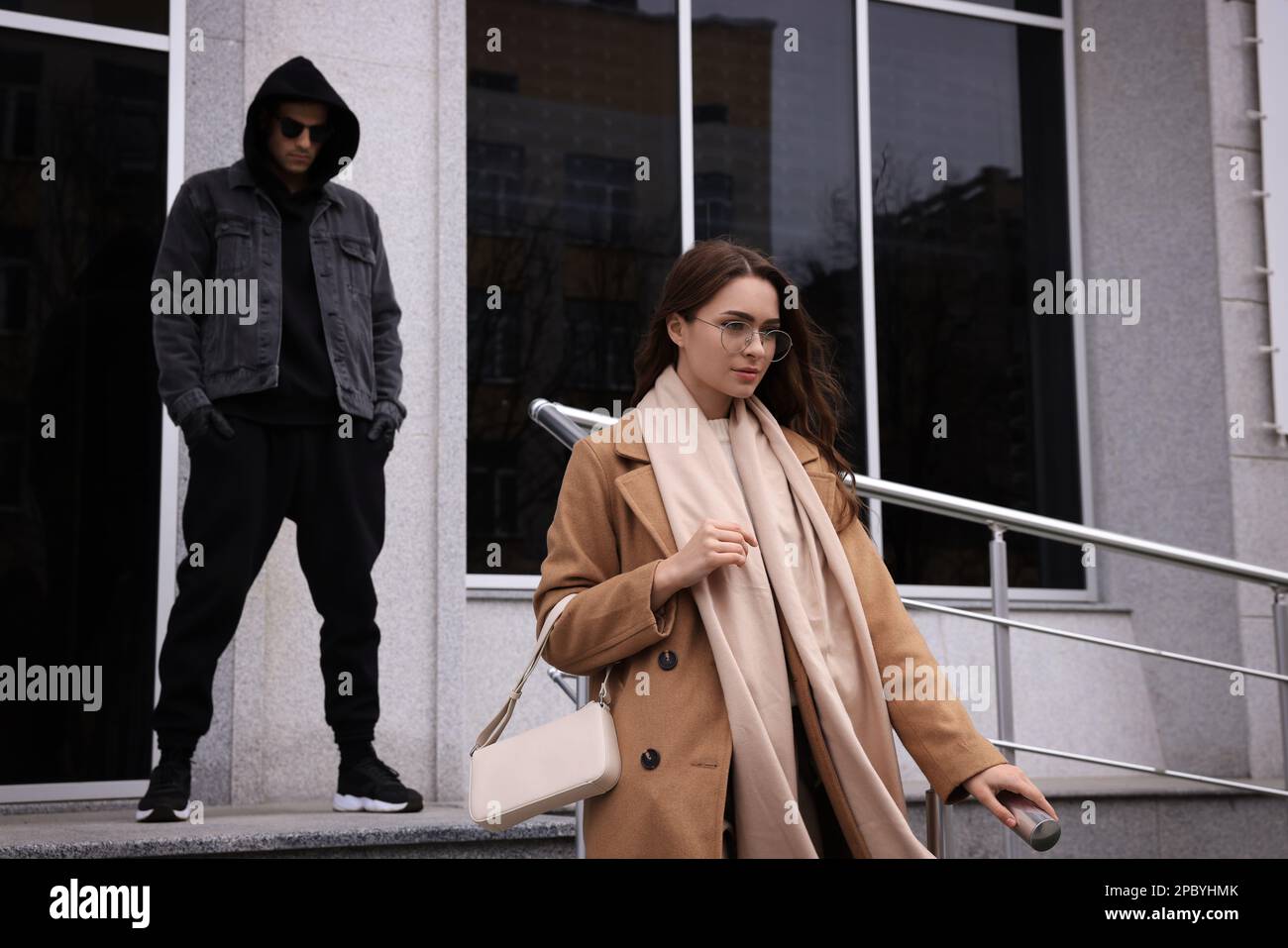 Man stalking young woman near building outdoors Stock Photo - Alamy