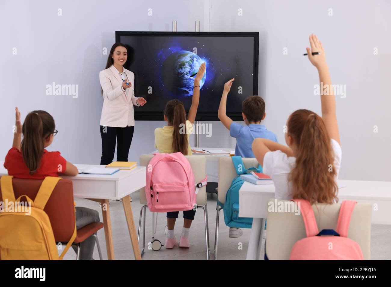 Teacher giving lesson to pupils near interactive board in classroom ...
