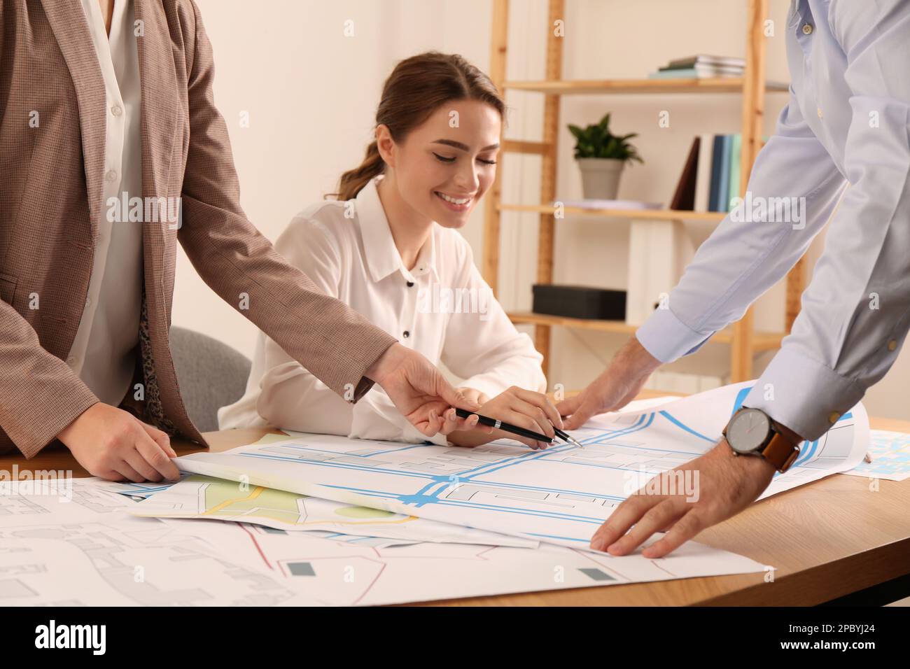 Professional cartographers working with cadastral map at table in ...