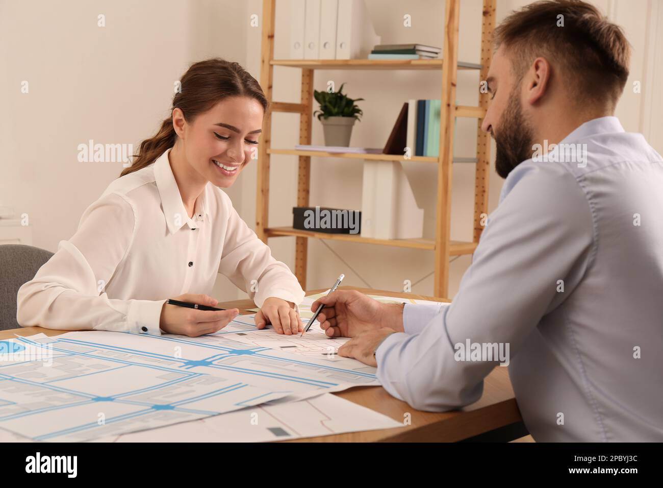 Professional cartographers working with cadastral map at table in ...
