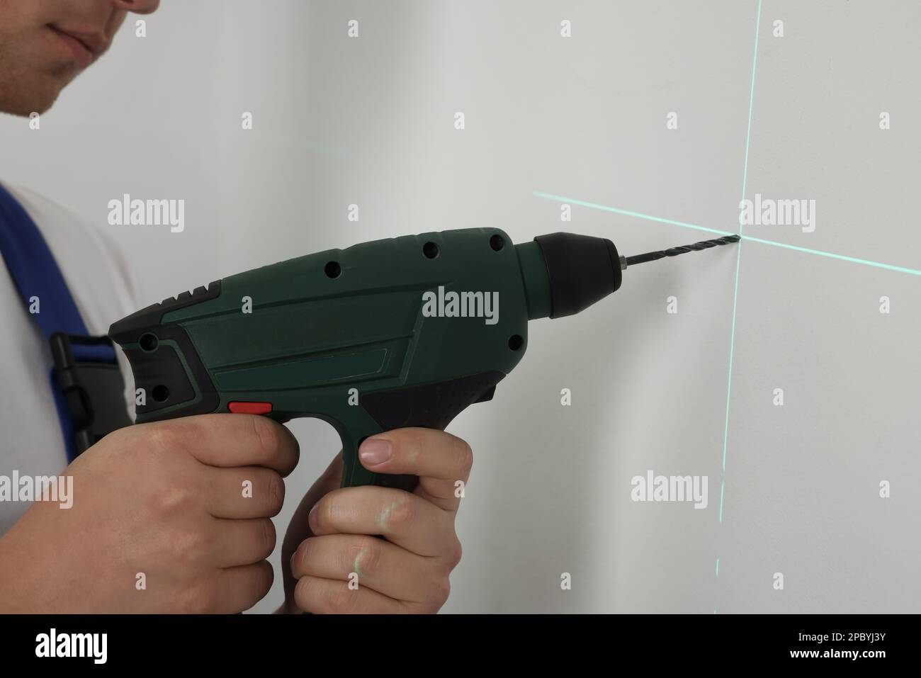 Man using cross line laser level for accurate measurement and drilling ...