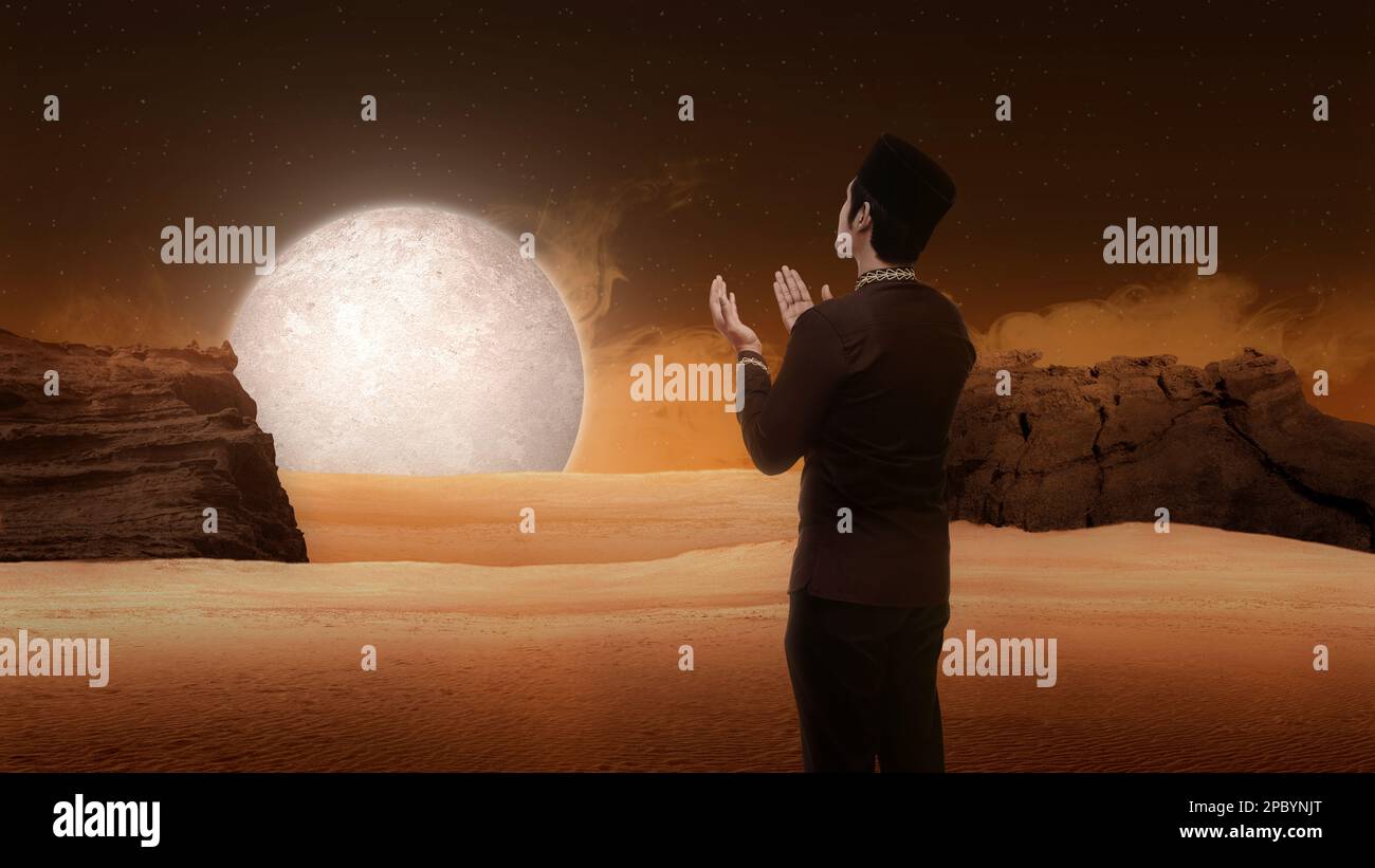 Muslim man standing while raised hands and praying in the desert Stock ...
