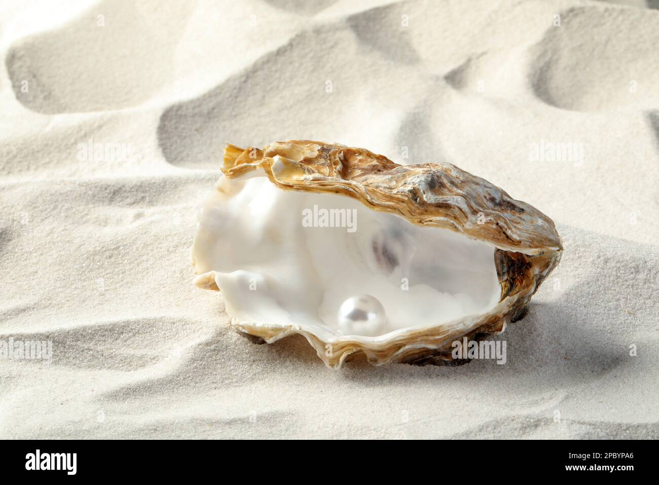 Open oyster with white pearl on sand Stock Photo - Alamy