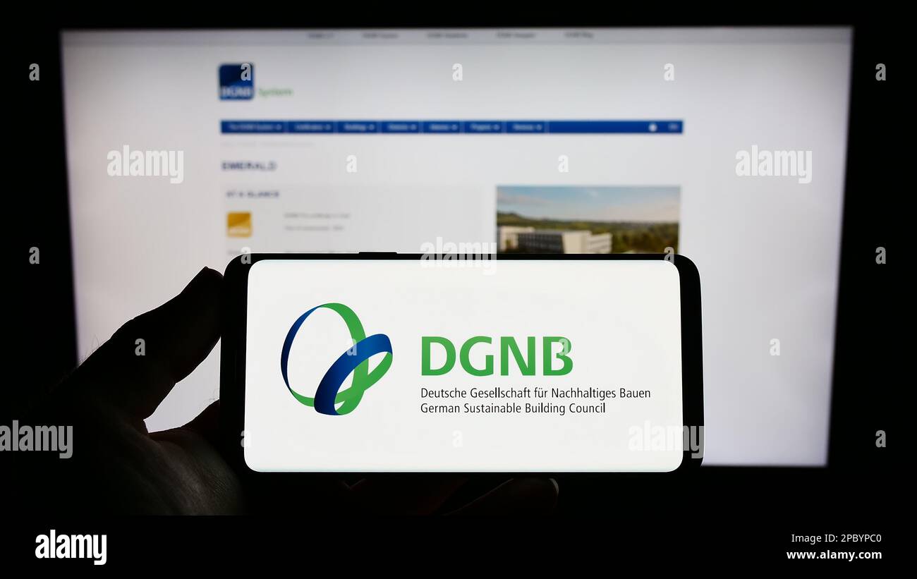 Person Holding Smartphone With Logo Of Deutsche Gesellschaft Für Nachhaltiges Bauen Dgnb On