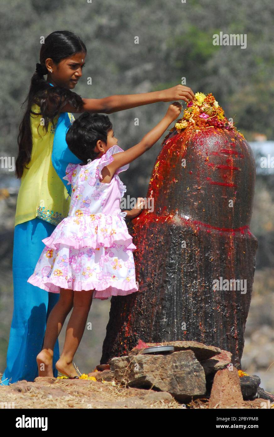 Young Hindu devotees perform rituals in front of a shivling, an idol ...