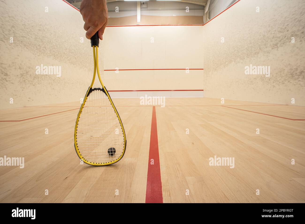 Male hand holding a racket inside a squash court. Low angle ...