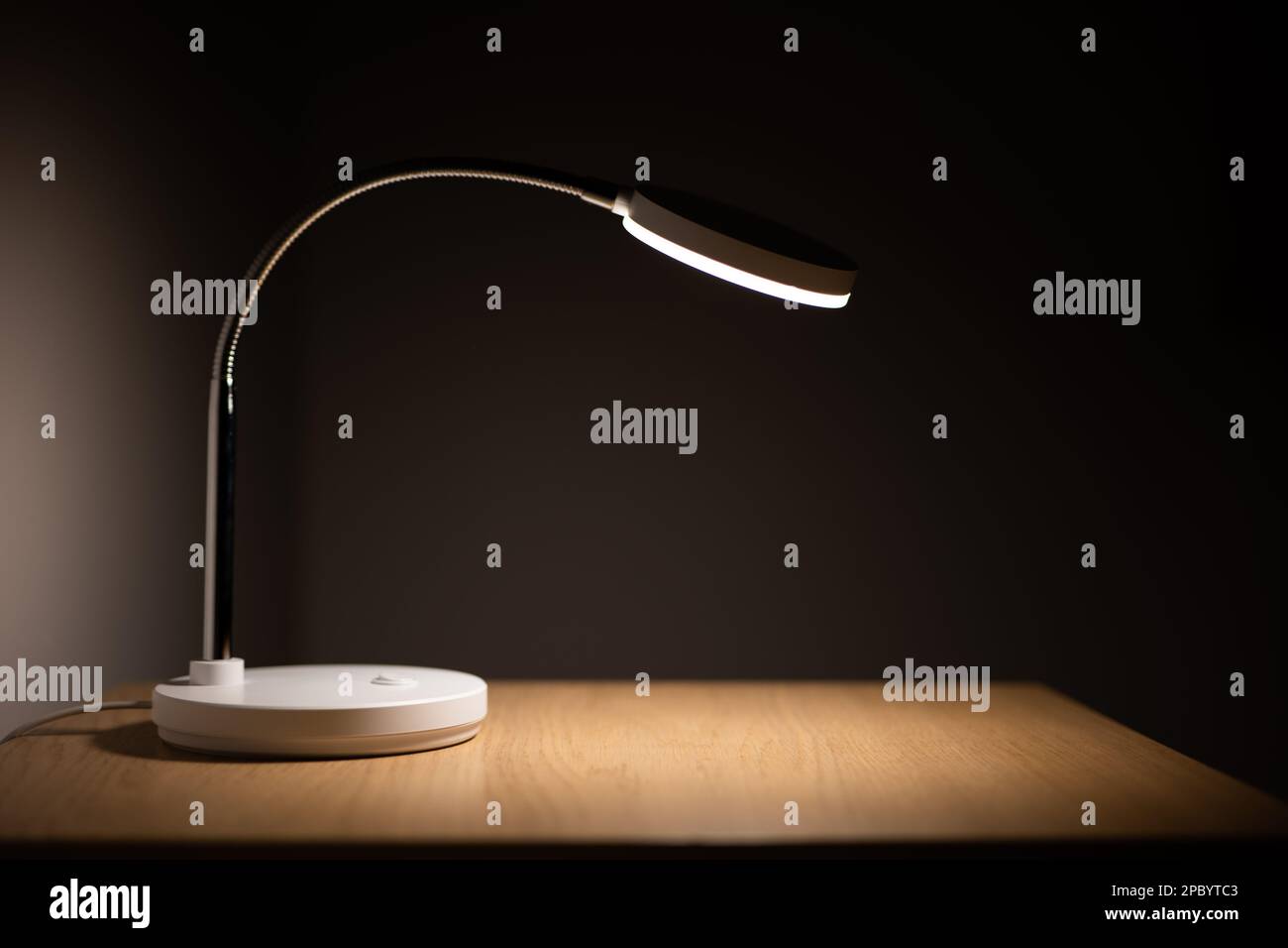 Bedside nightstand LED lamp illuminating. Dark moody scene, no people ...