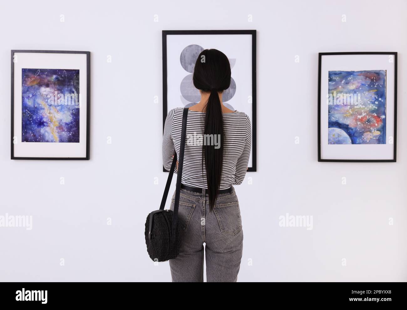 Young woman at exhibition in art gallery, back view Stock Photo - Alamy
