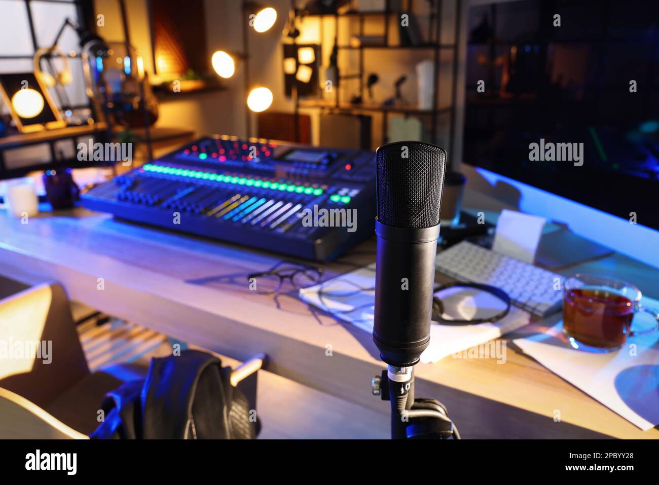 Microphone near table with professional mixing console in radio studio ...