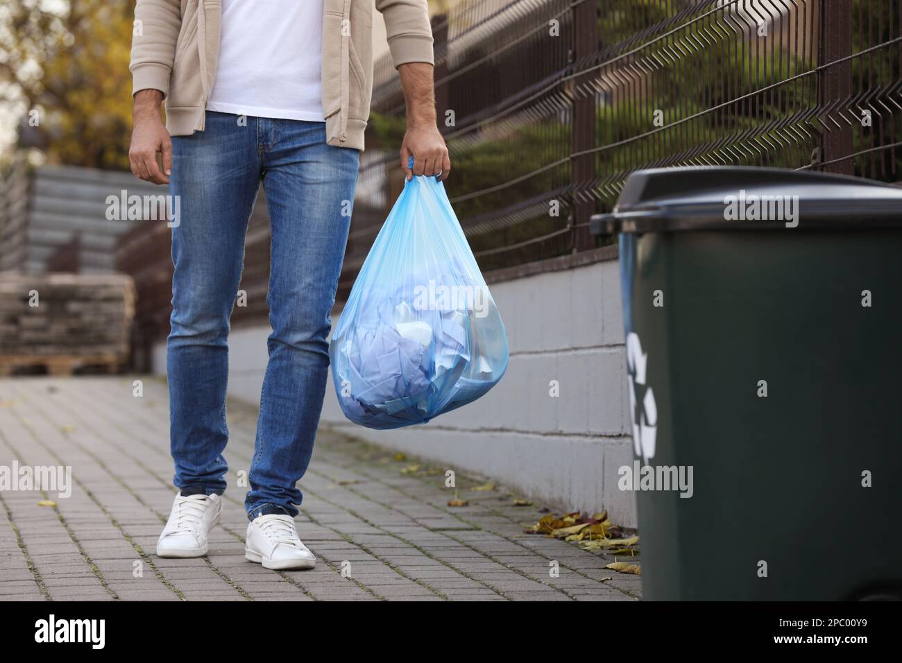 Man carrying garbage bag to recycling bin outdoors, closeup Stock Photo ...