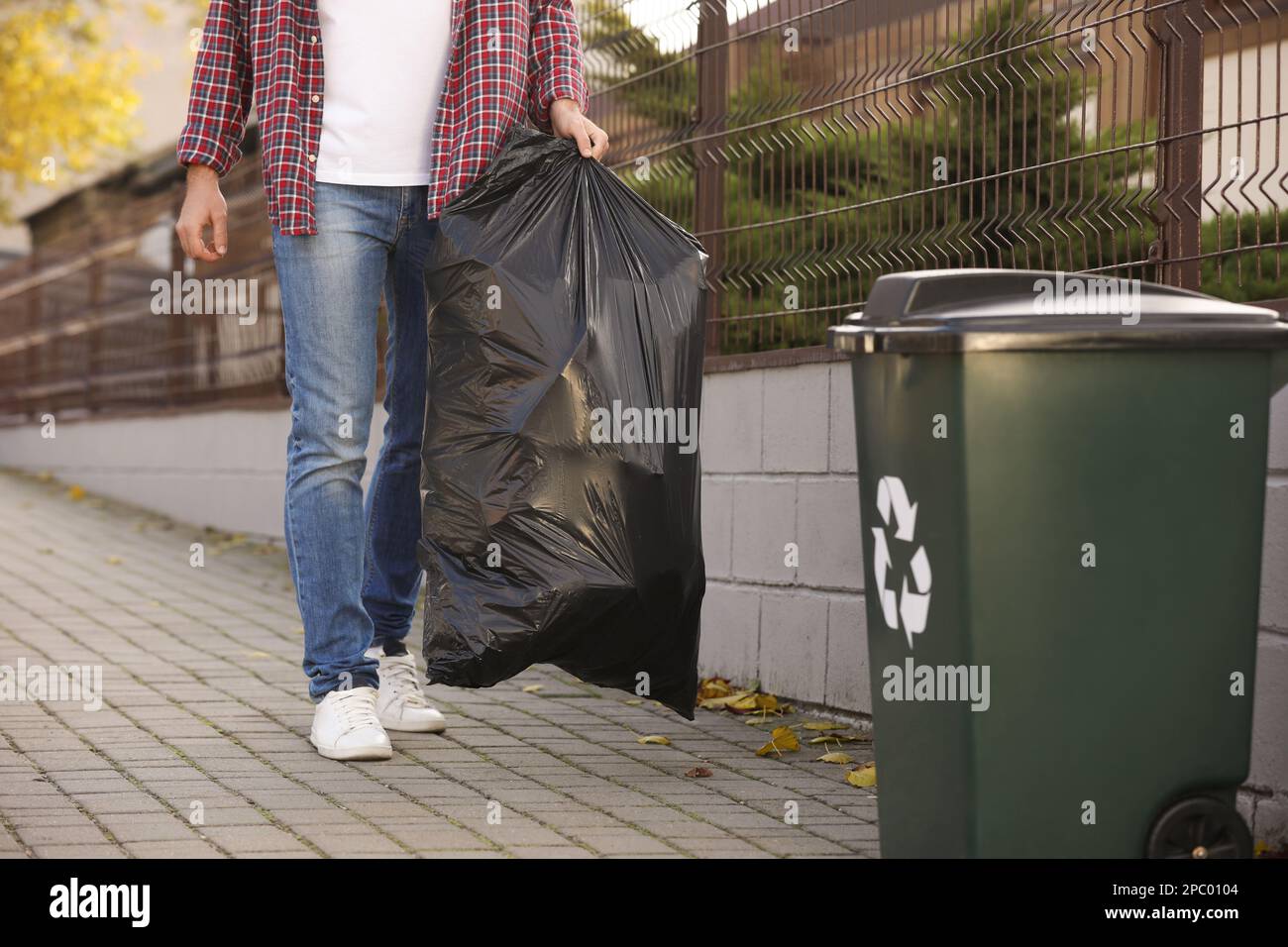 Man carrying garbage bag to recycling bin outdoors, closeup Stock Photo ...