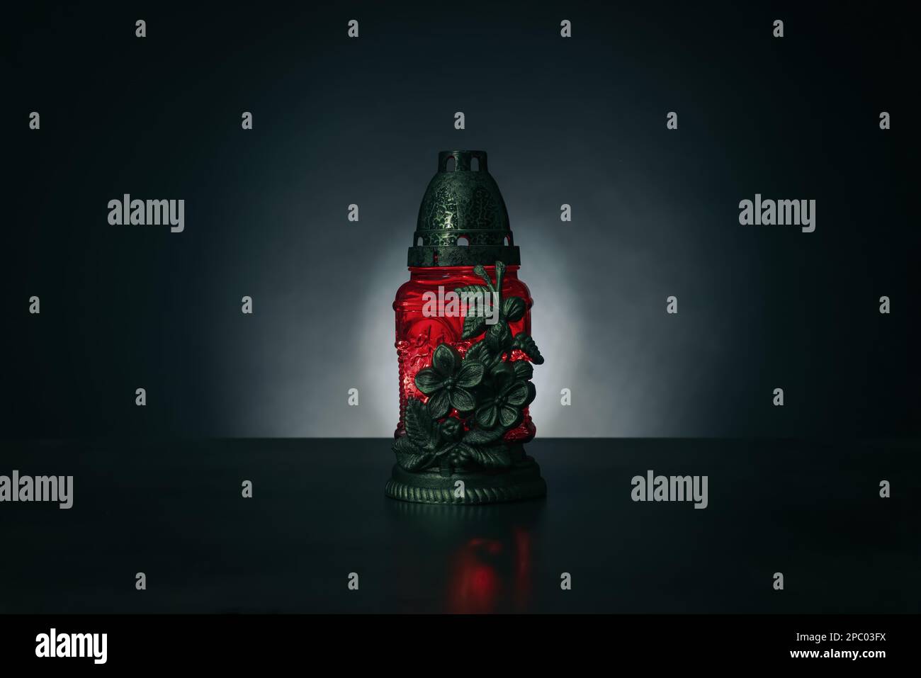 Beautiful glowing red grave light on table in darkness. Symbol of ...