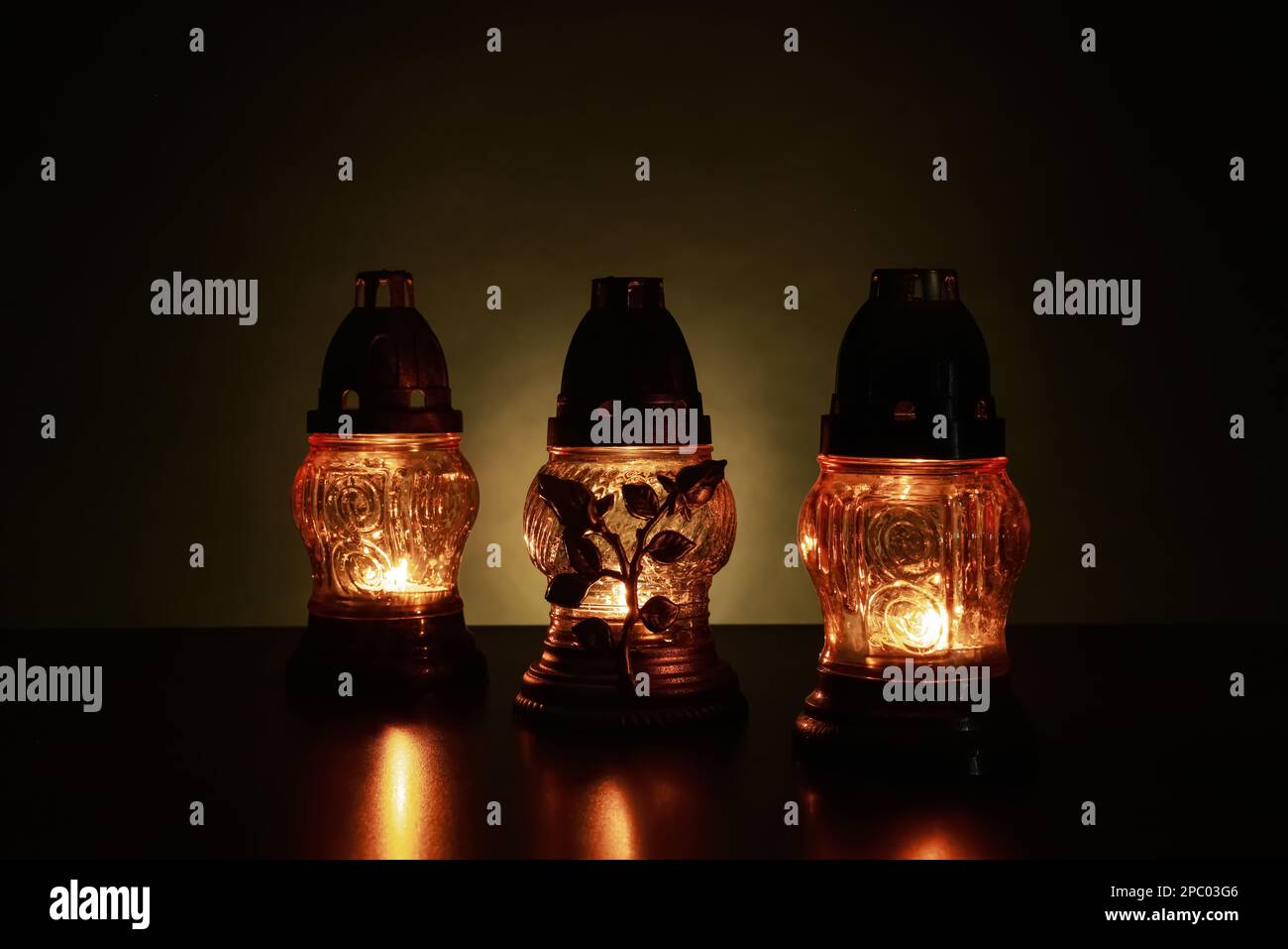 Beautiful glowing grave lights on table in darkness. Symbol of ...