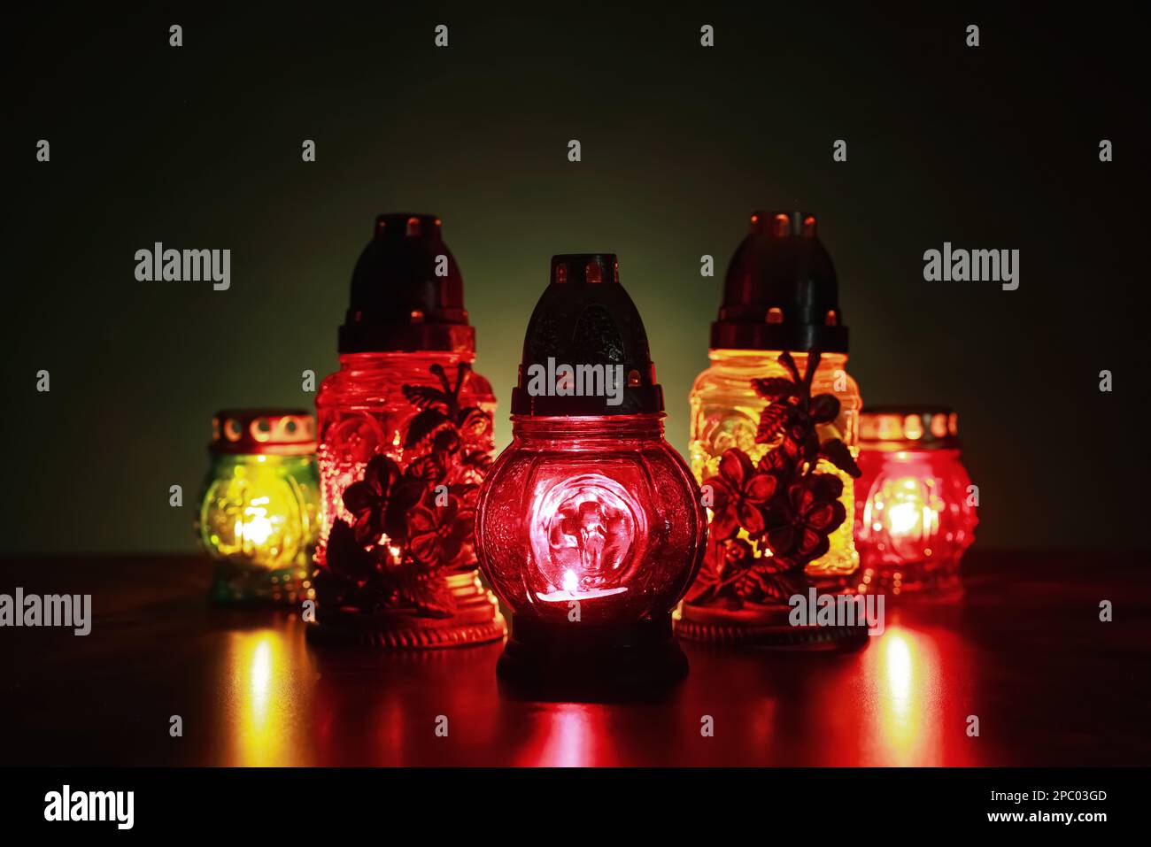 Beautiful glowing grave lights on table in darkness. Symbol of ...