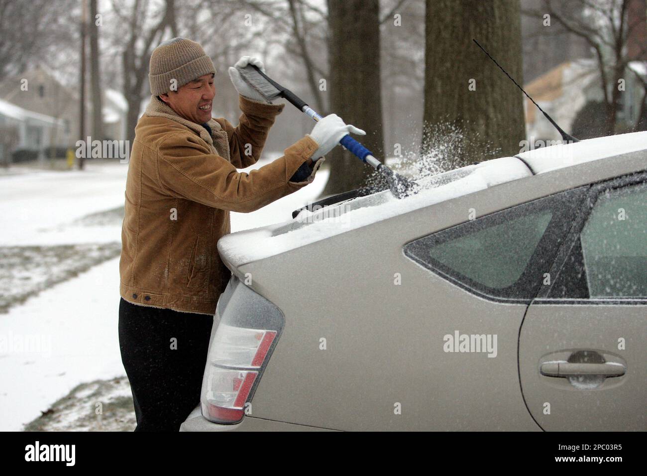 Perry Ning scrapes the ice off the rear window of his car in North ...