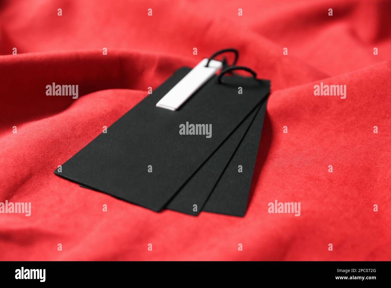 Blank black tags on red fabric, closeup. Space for text Stock Photo - Alamy