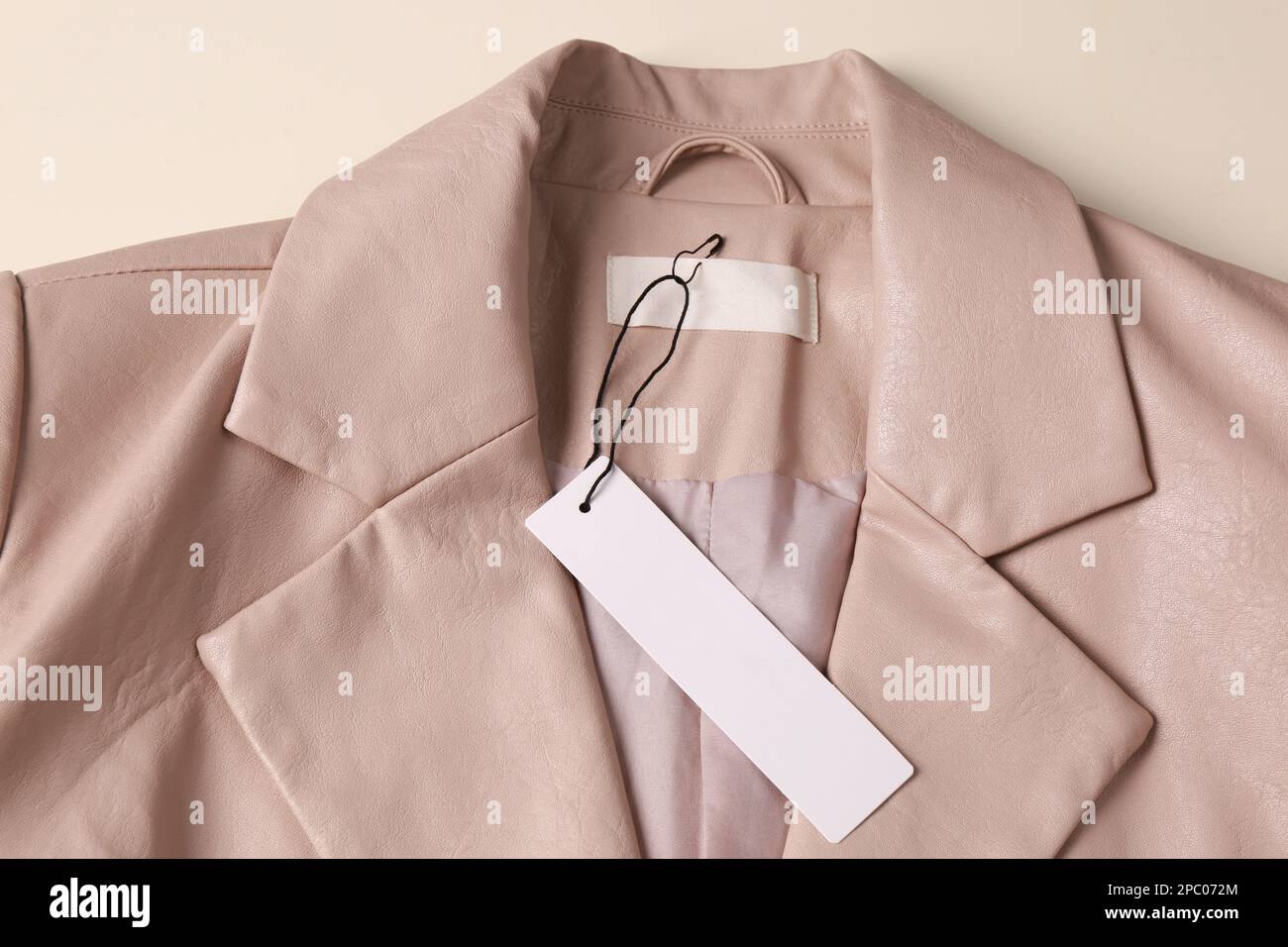Blank white tag on beige leather jacket, top view. Space for text Stock ...