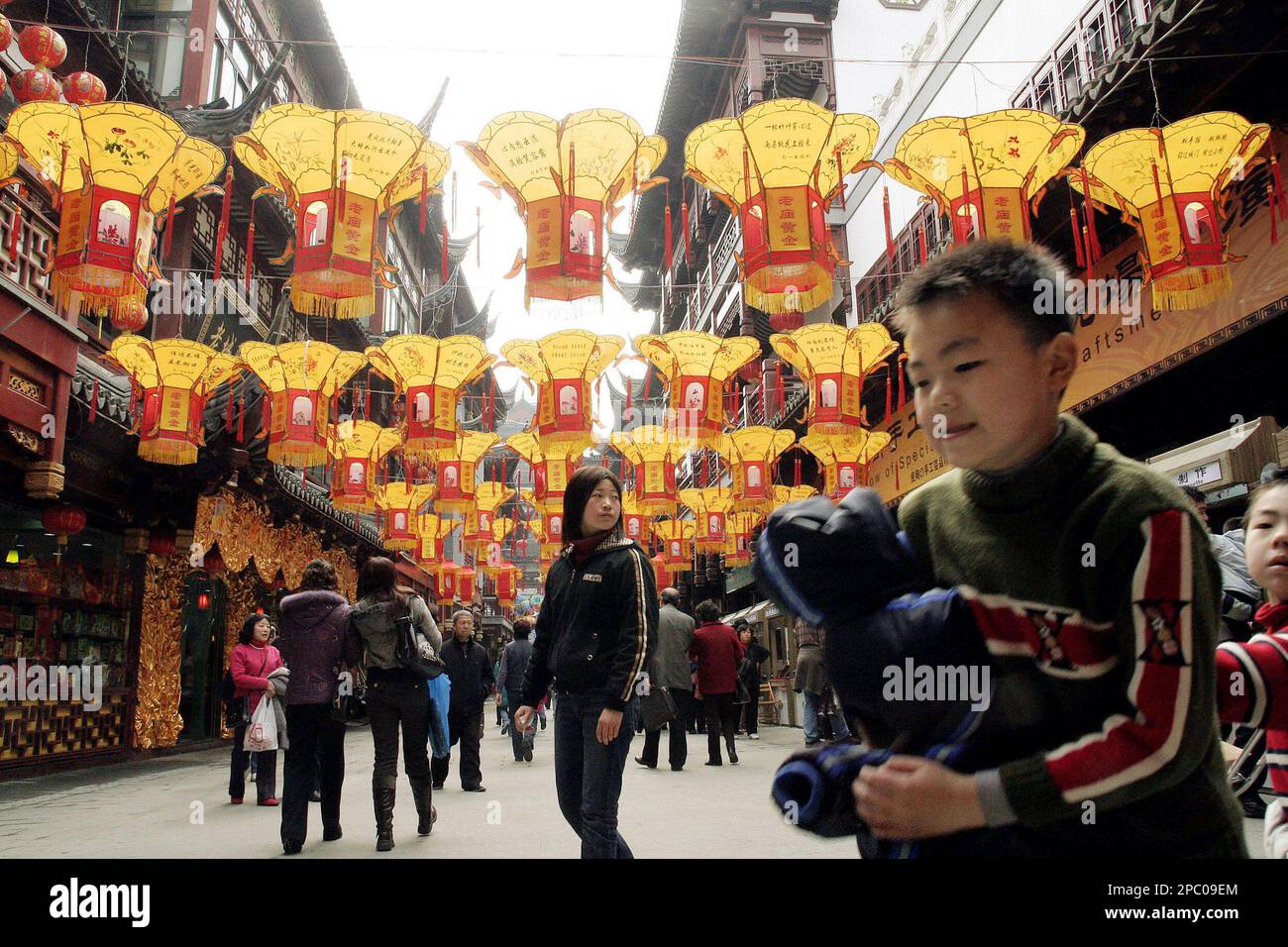 People walk along a street adorned with lanterns hung for the upcoming ...