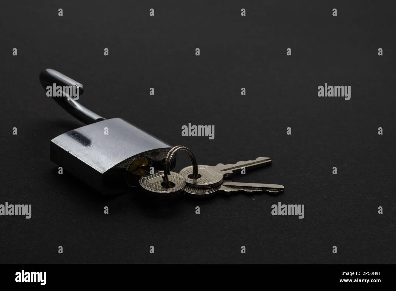 Open steel padlock with three keys on black surface Stock Photo - Alamy