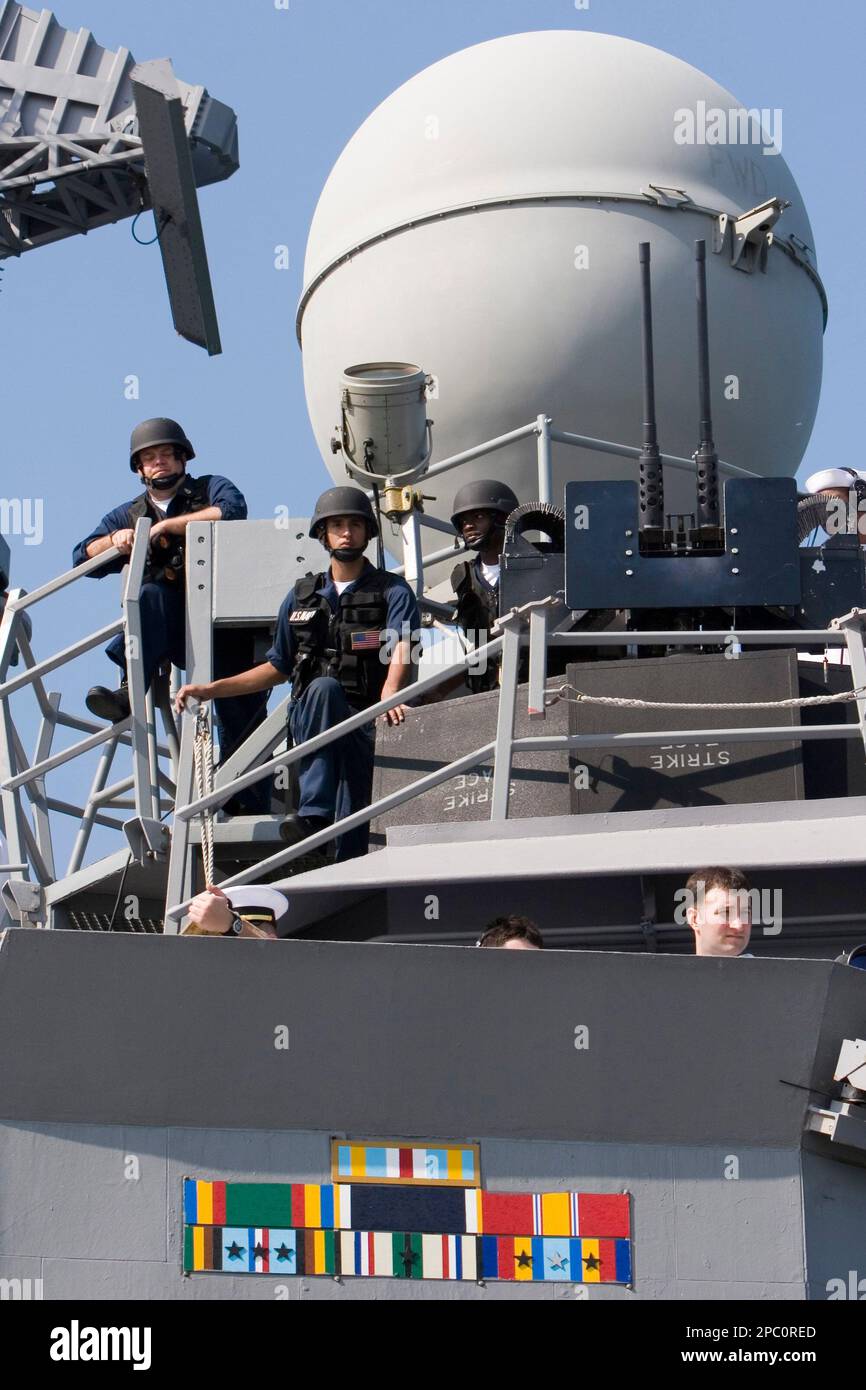 Crew members look on from their USS Gary warship upon their arrival to ...