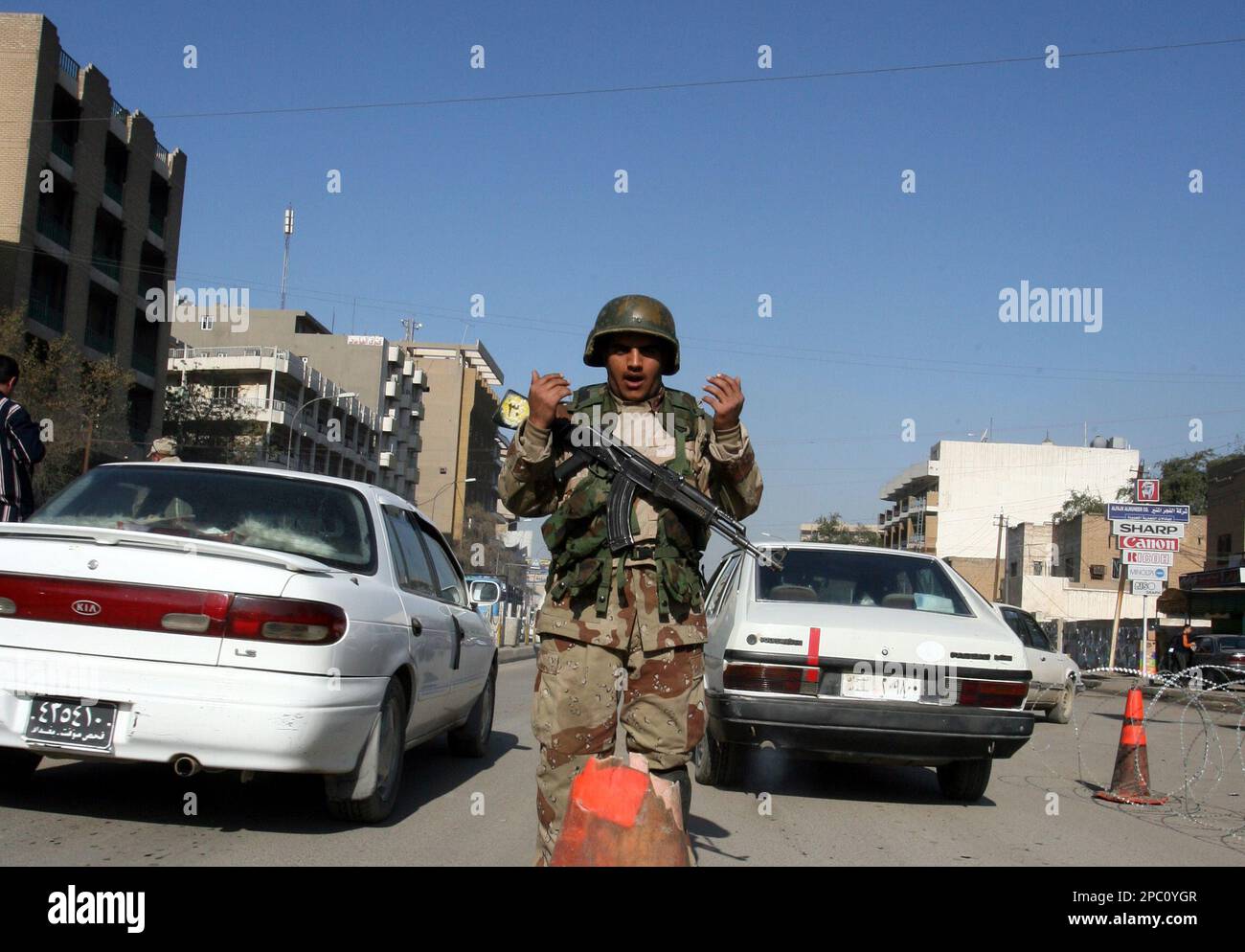 An Iraqi army soldier controls traffic at a vehicle checkpoint in ...