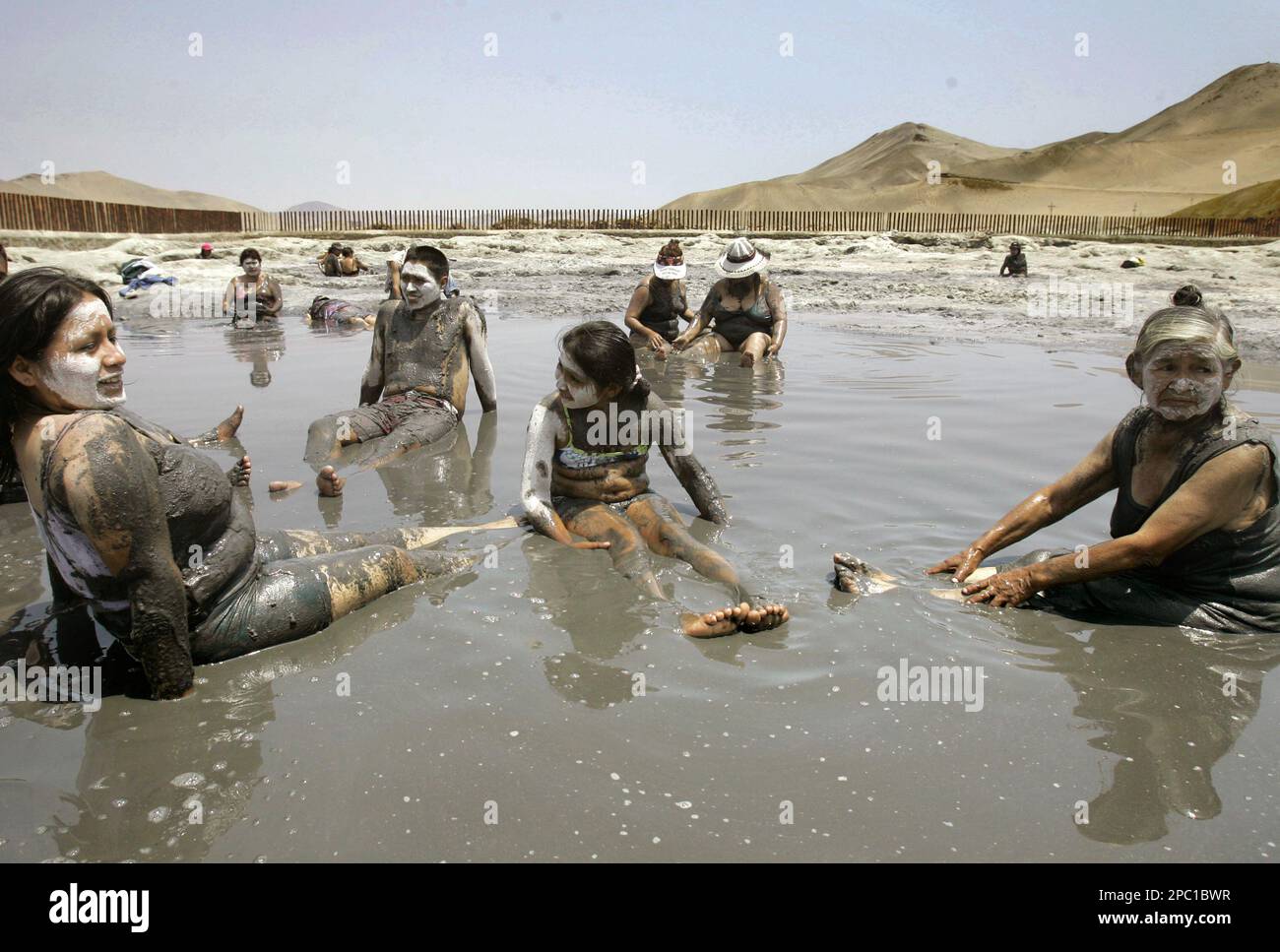 Covered with black mud from head to toe, people plunge into a pond ...