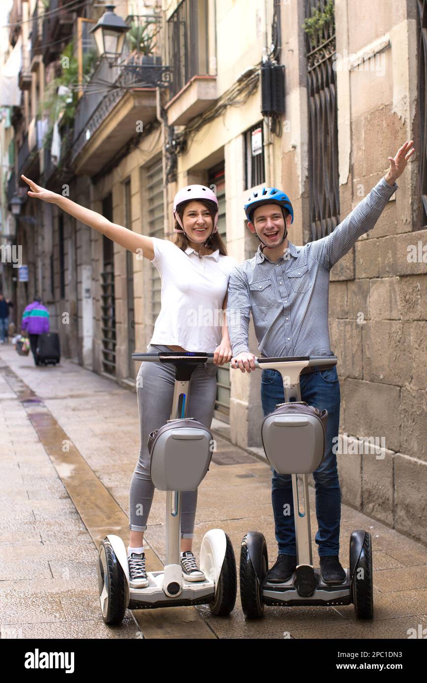 young couple guy and girl walking on segway in streets of european city ...