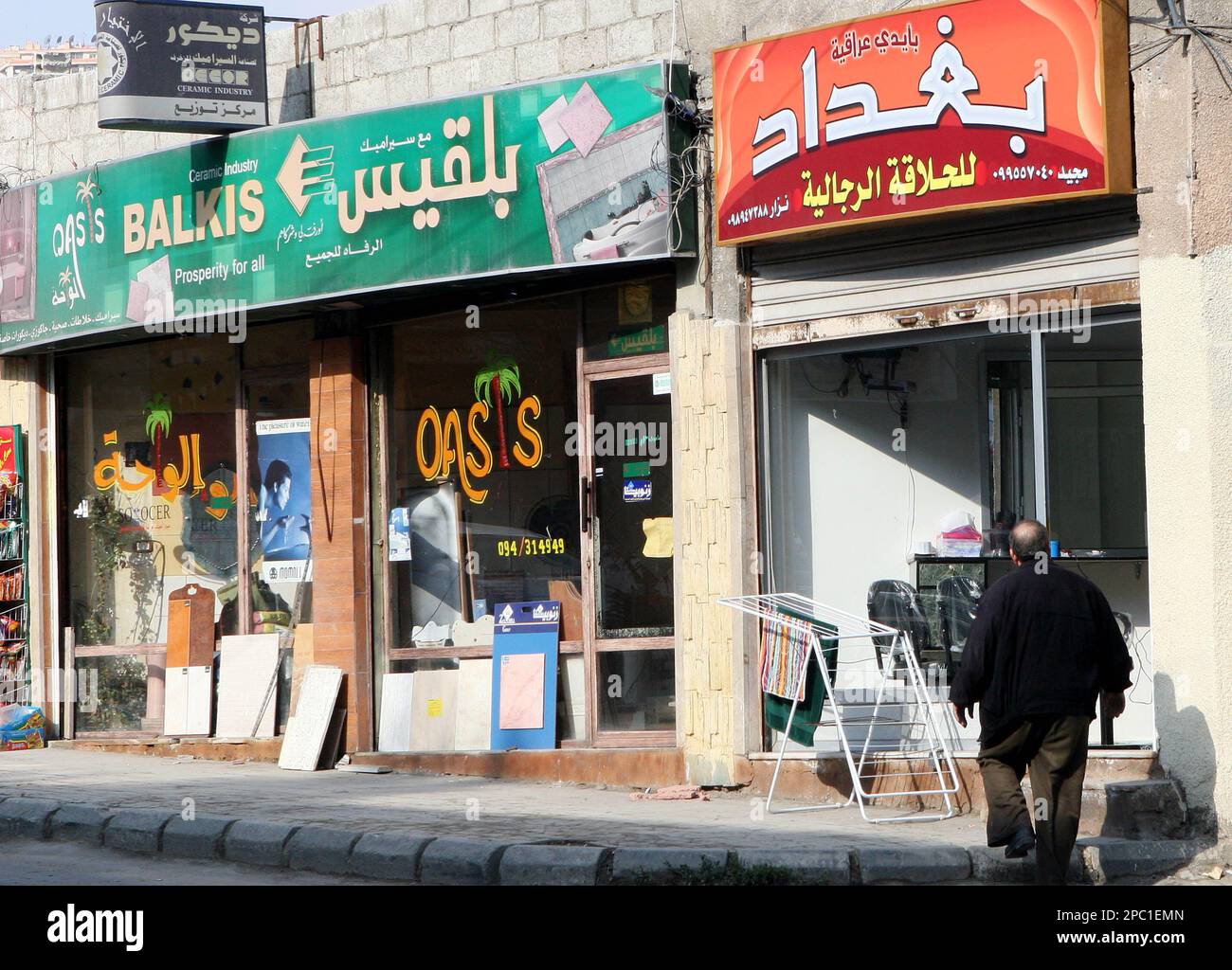 A man walks in front of the "Baghdadi barber" shop, right, in Damascus ...