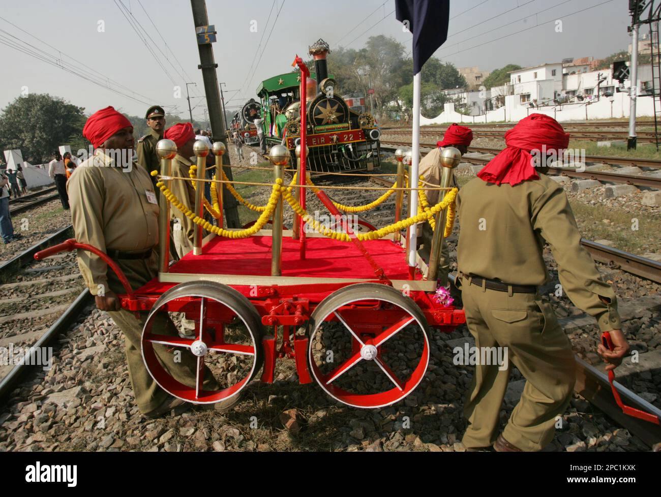 Railway workers lift a manually pushed rail trolley to another track in ...
