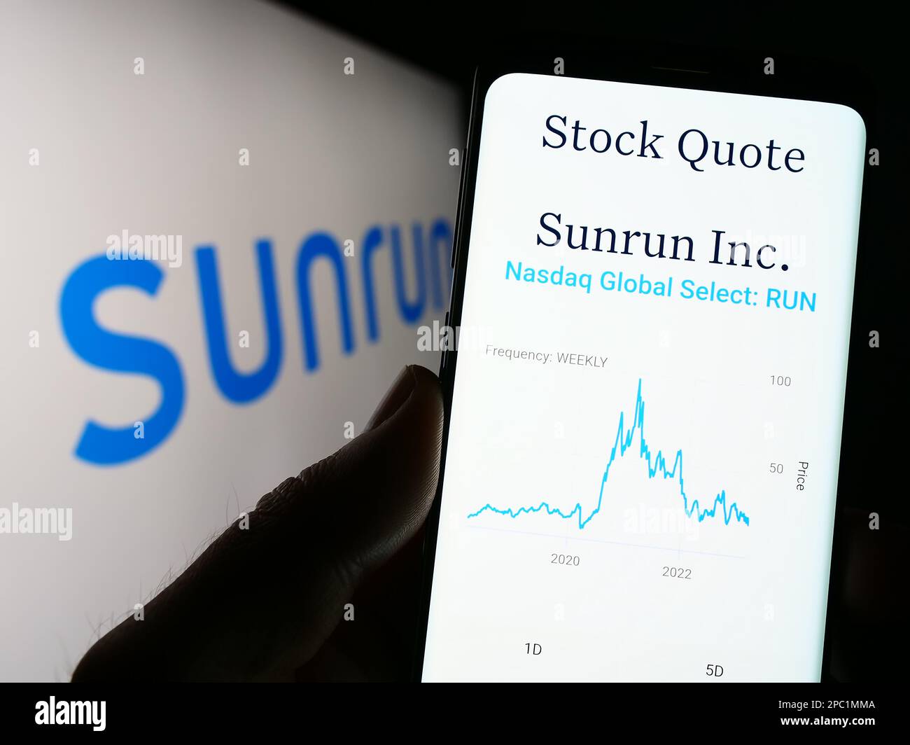 Person holding cellphone with webpage of US solar energy company Sunrun Inc. on screen in front ...