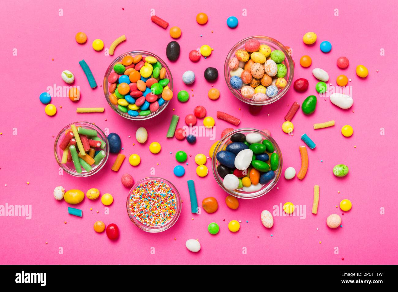 different colored round candy in bowl and jars. Top view of large ...