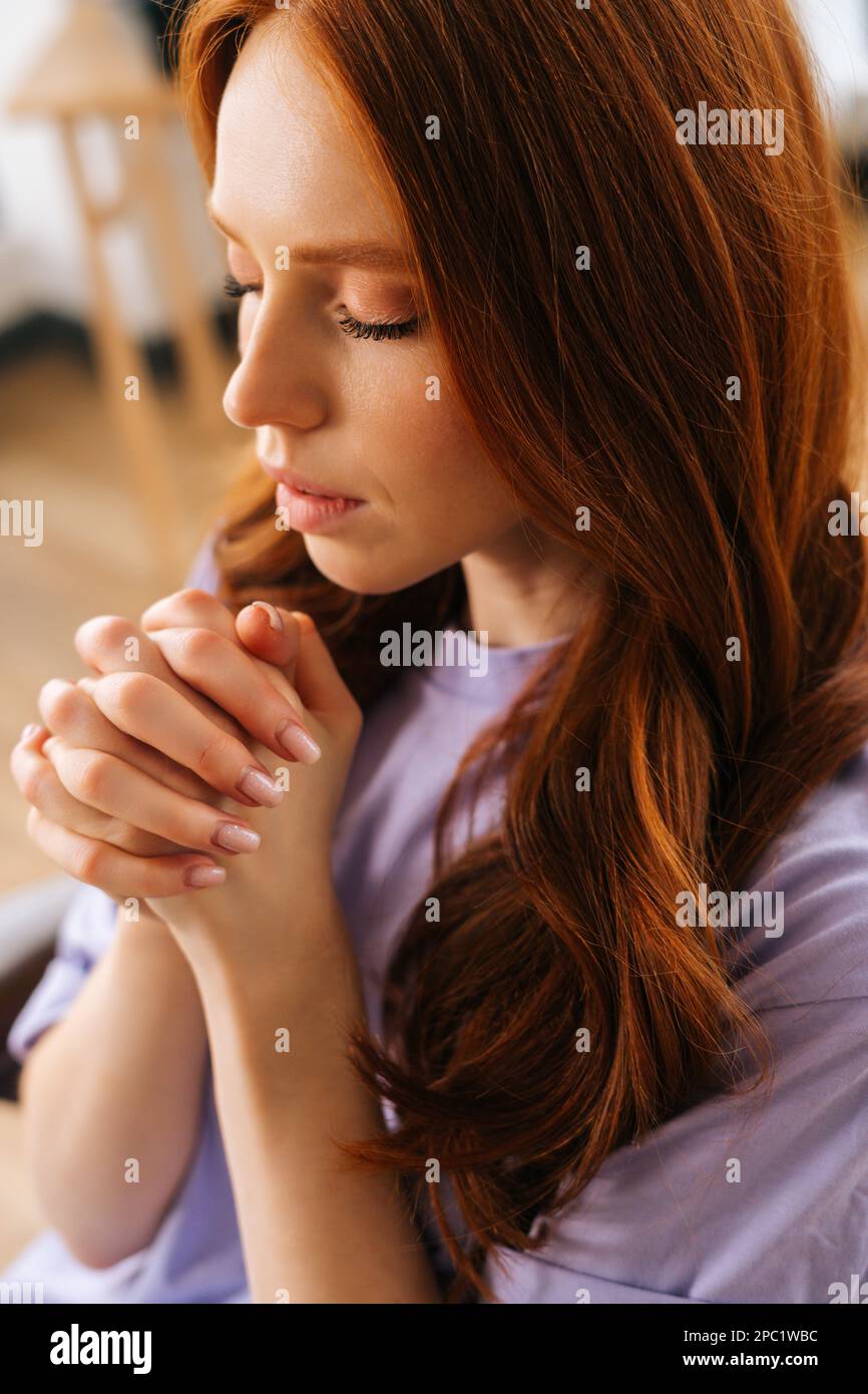 Vertical closeup portrait of sad young woman sincerely praying with ...