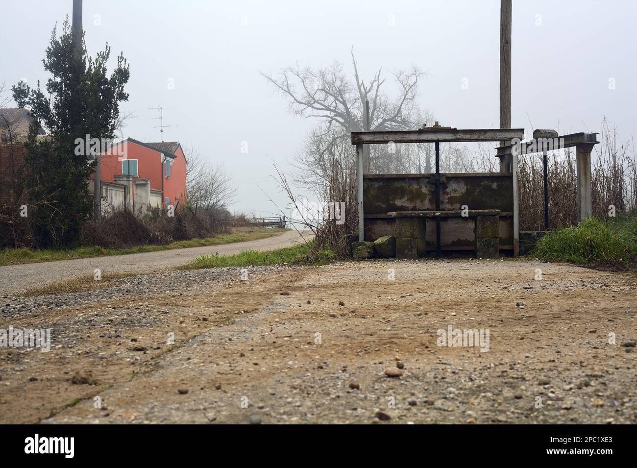 Dry irrigation channel and a rusty weir on a foggy day in the italian ...