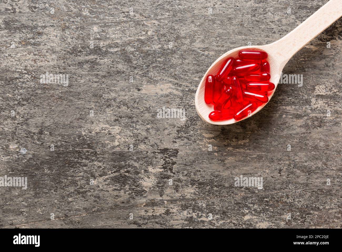 Vitamin capsules in a spoon on a colored background. Pills served as a ...