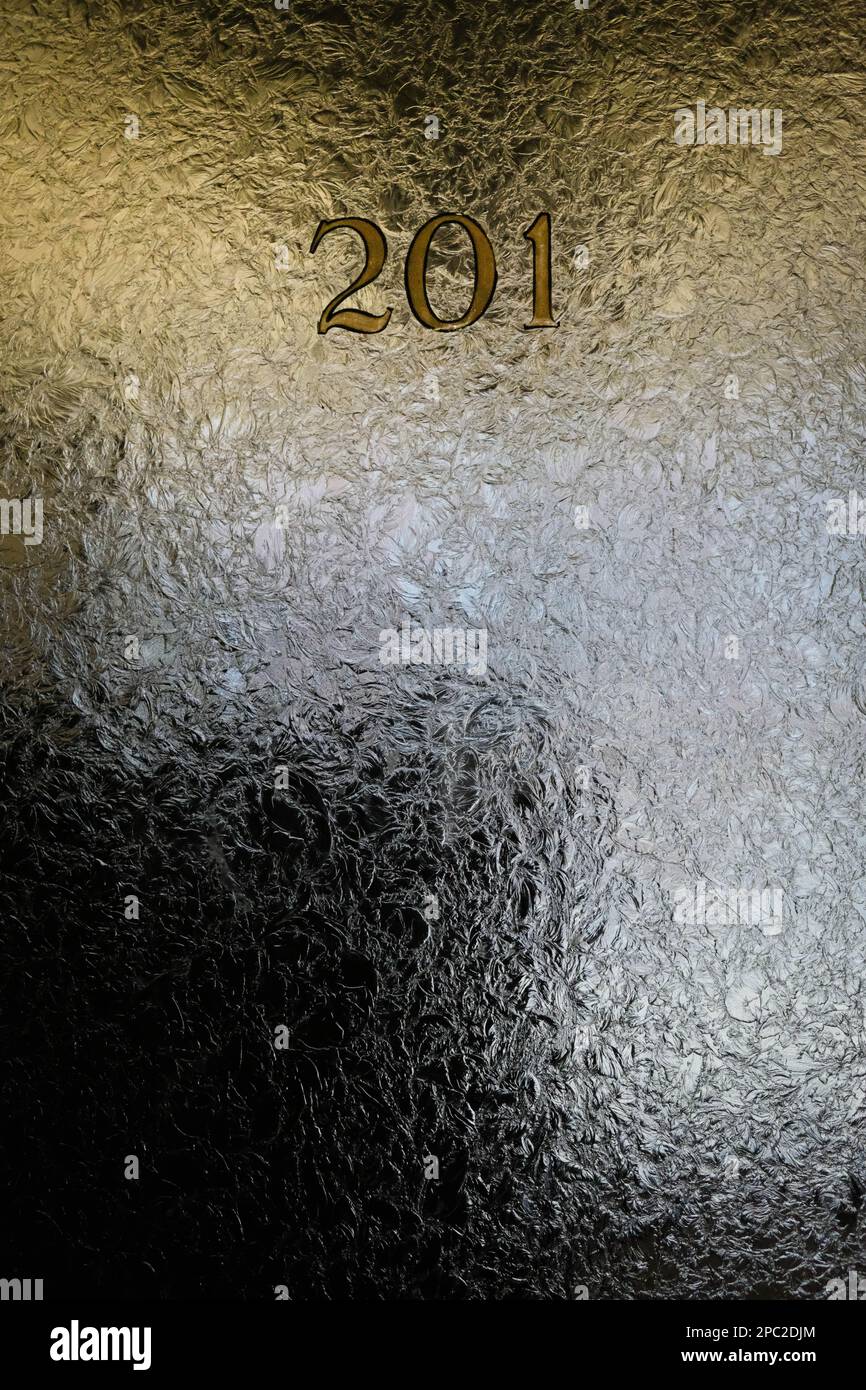 Crackled glass in office door window with numbers and dim lighting ...
