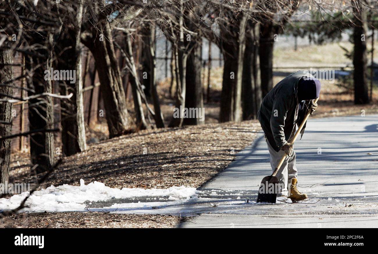 A workman chips away an icy patch on a walkway at the Stone Zoo in ...