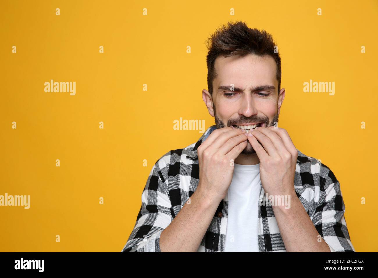 Man biting his nails on yellow background. Space for text Stock Photo ...