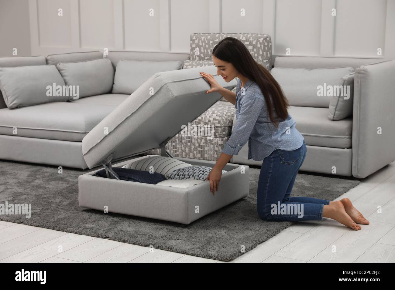 Woman opening modular sofa section with storage in living room Stock ...